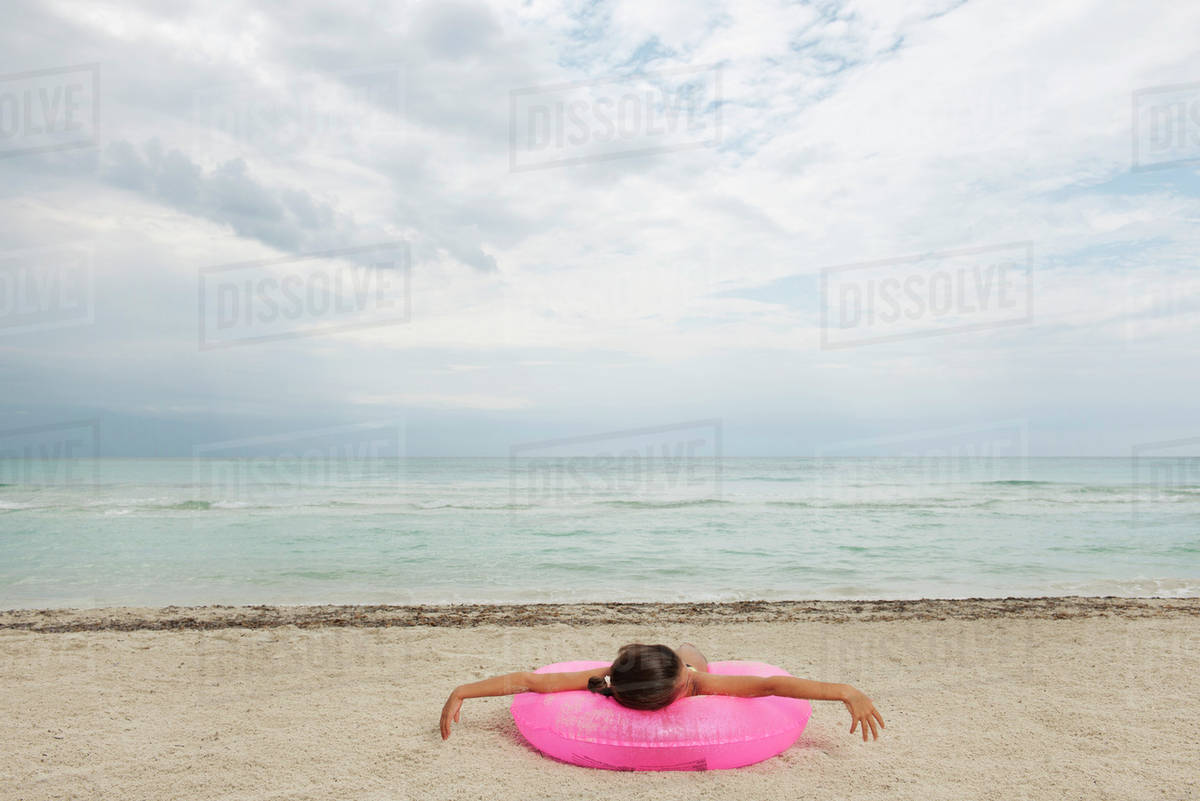 Girl lying on inflatable ring on beach, rear view - Royalty-free Stock ...
