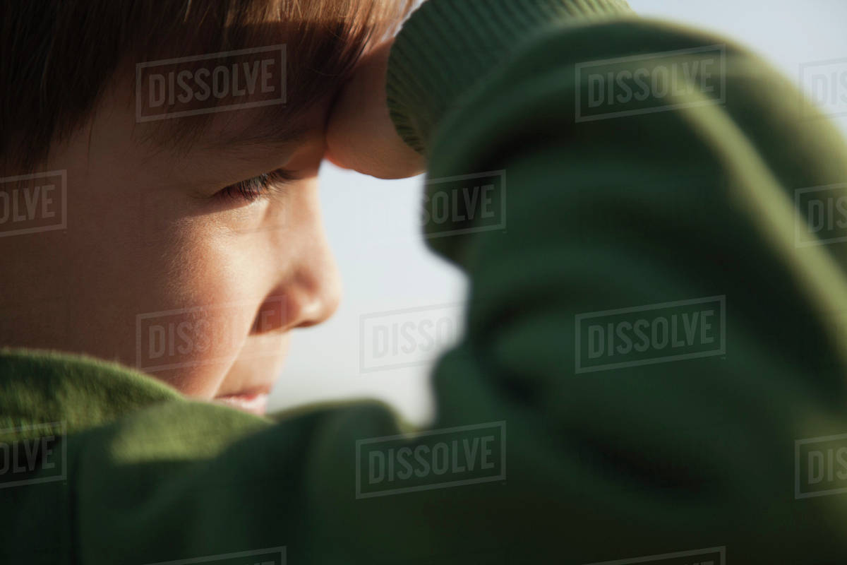 Boy shading eyes, side view - Royalty-free Stock Photo | Dissolve