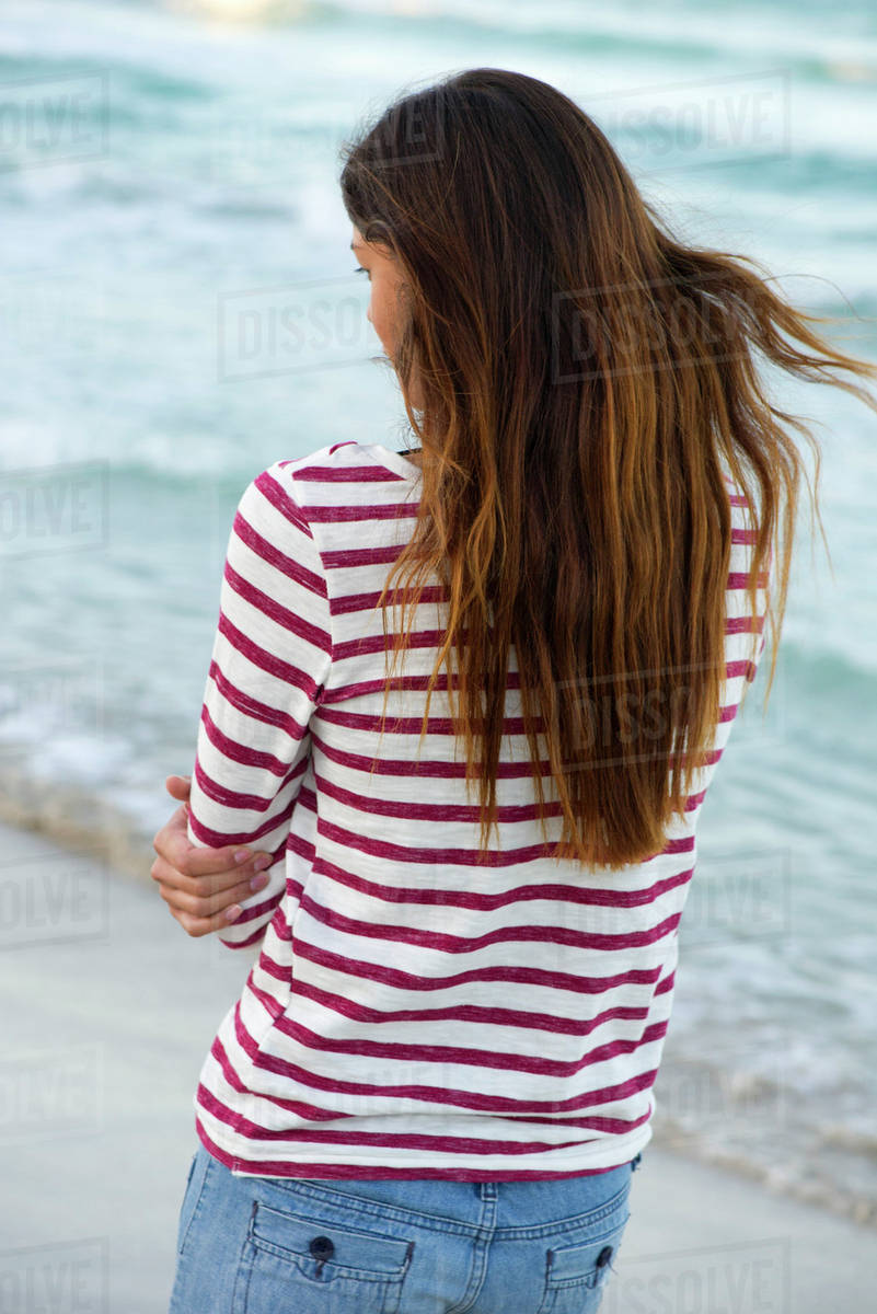 Young woman standing at beach, rear view - Royalty-free Stock Photo ...
