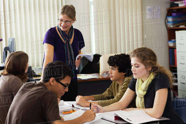Teacher helping high school students with classwork - Royalty-free ...