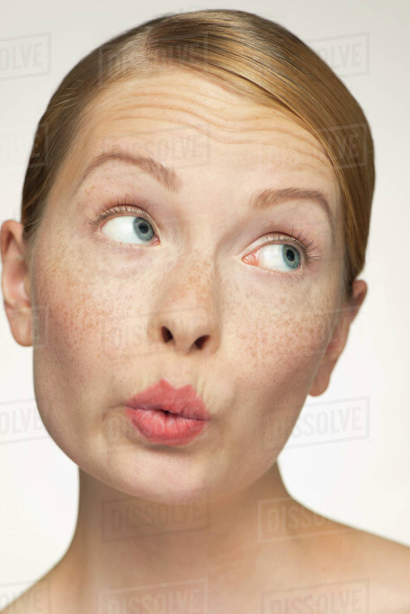 Young woman pursing lips - Stock Photo - Dissolve