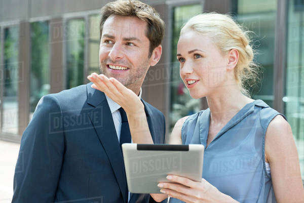 Real estate agent with digital tablet showing property to potential ...