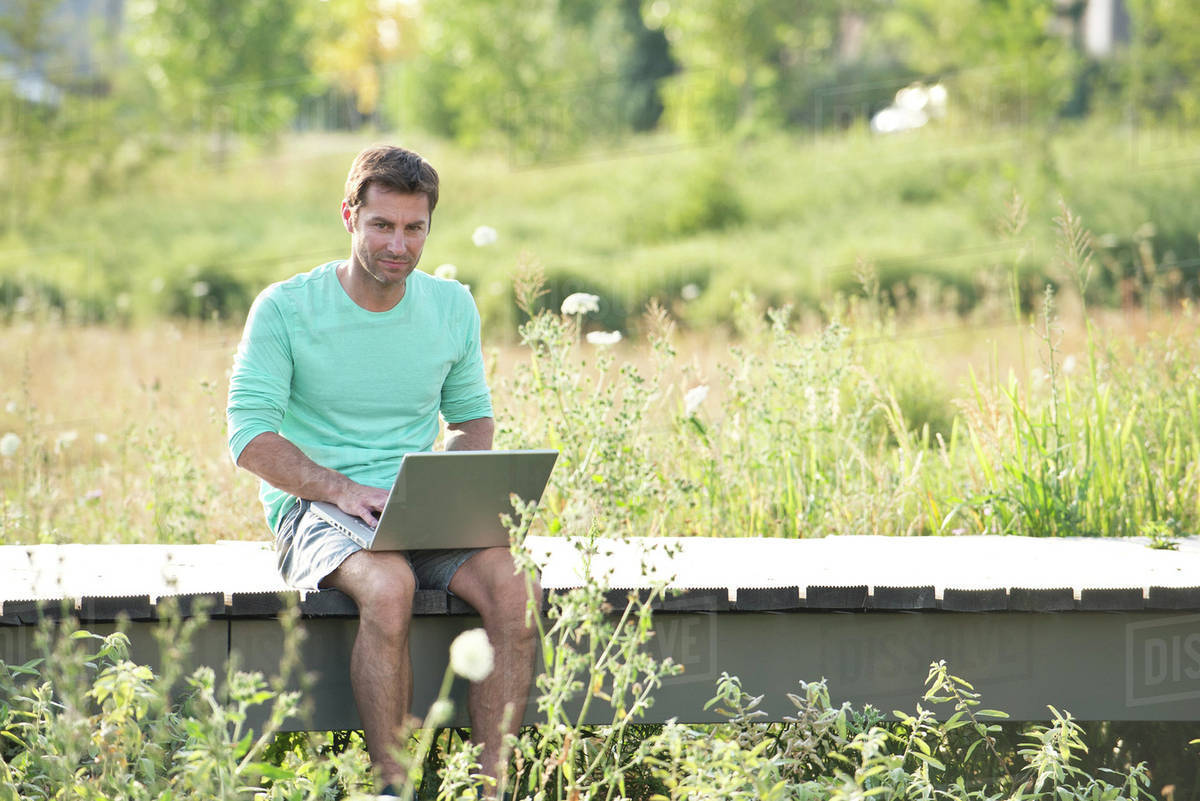 Man using laptop computer while sitting out in nature - Stock Photo ...