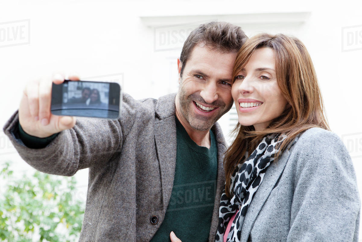 Couple taking self portrait with camera phone - Stock Photo - Dissolve