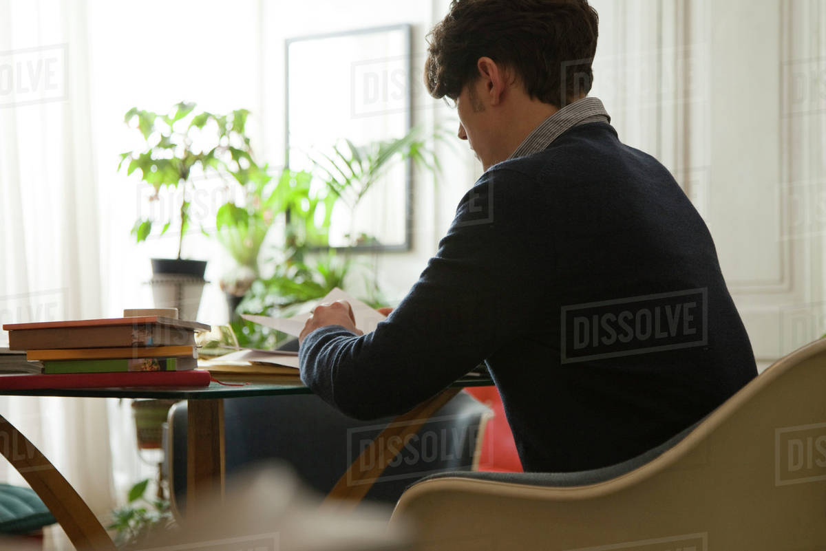 Man sitting at table reading - Royalty-free Stock Photo | Dissolve