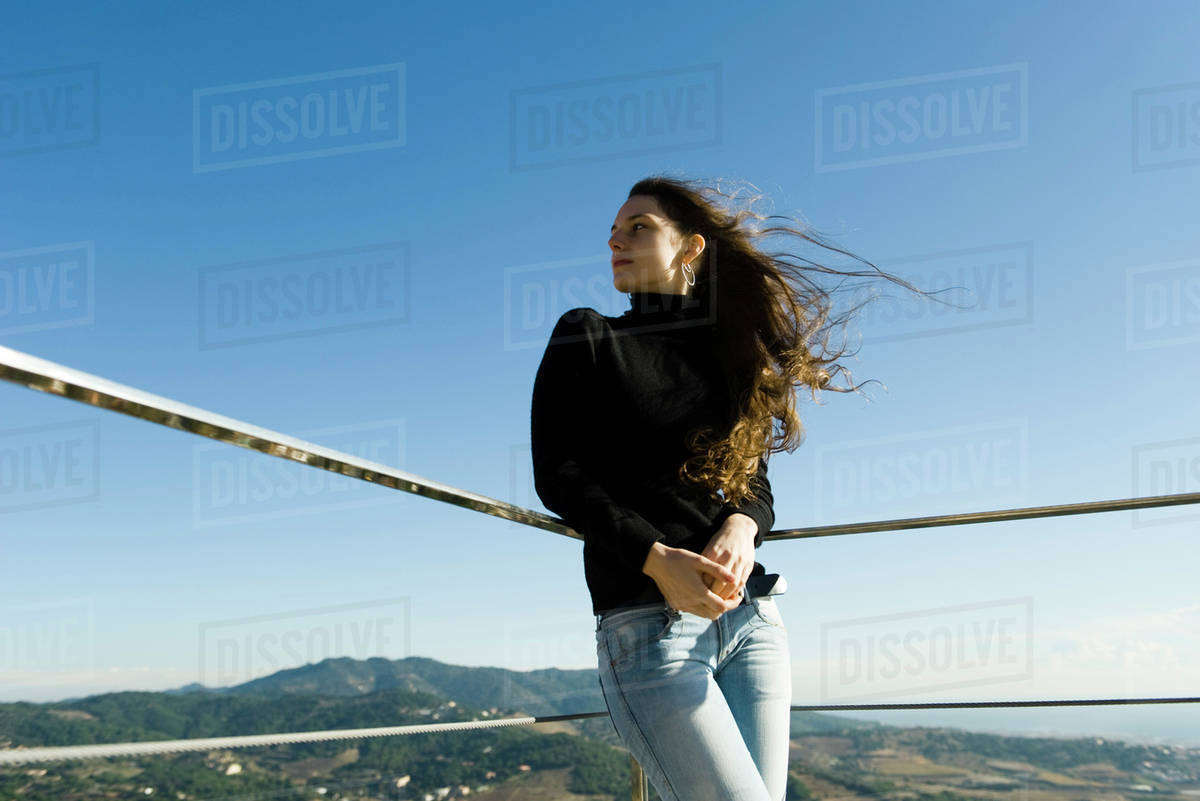 Woman leaning against railing, looking at view - Royalty-free Stock ...