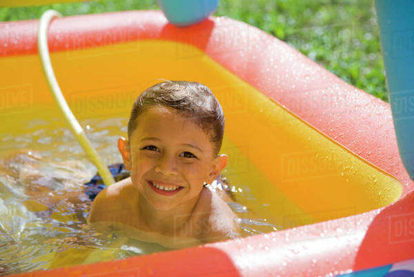 Little boy playing in wading pool, portrait - Stock Photo - Dissolve