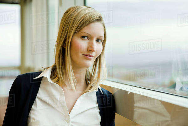 Woman leaning against window, portrait - Stock Photo - Dissolve