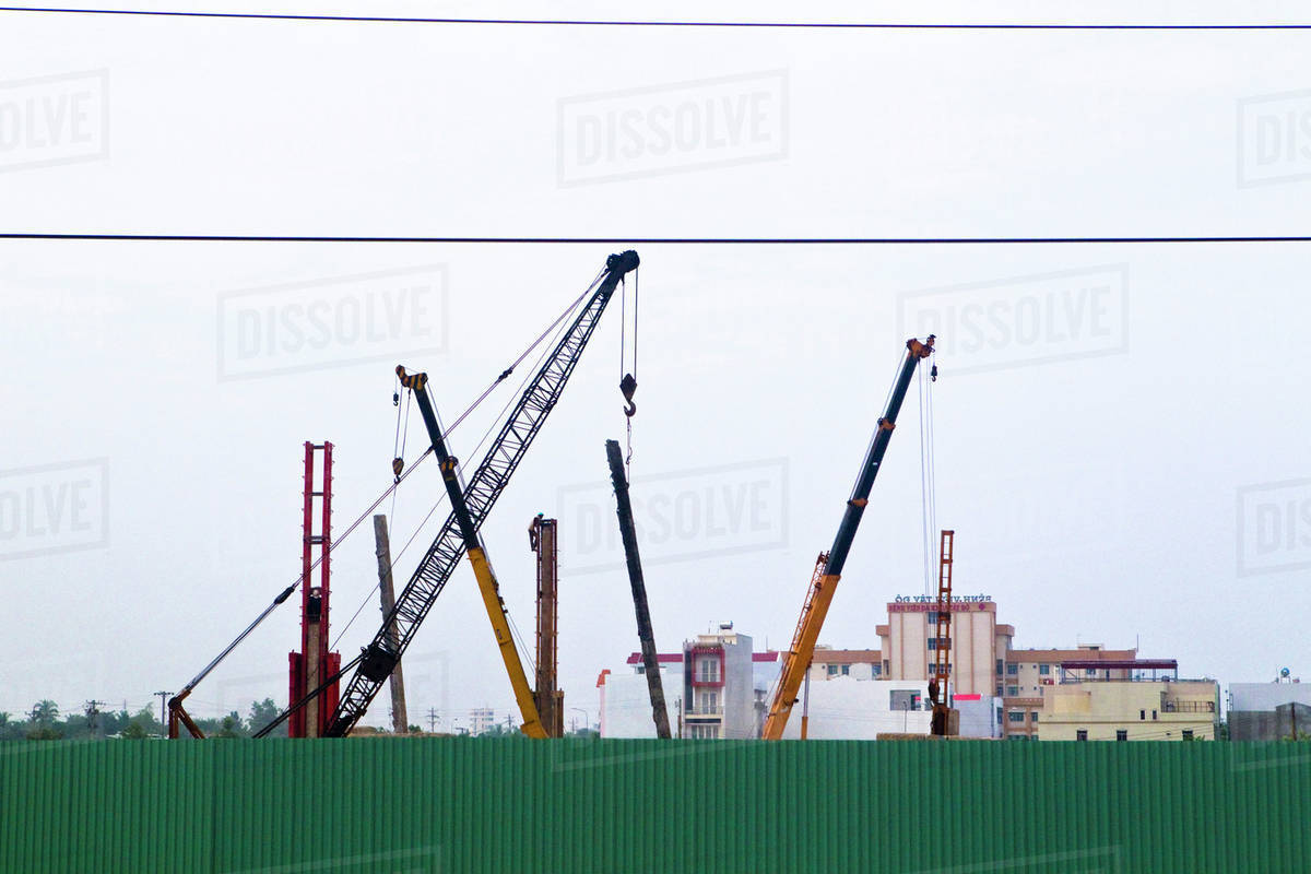 Cranes behind corrugated metal fence - Stock Photo - Dissolve