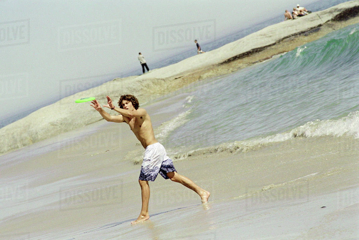 Male catching frisbee on beach - Royalty-free Stock Photo | Dissolve