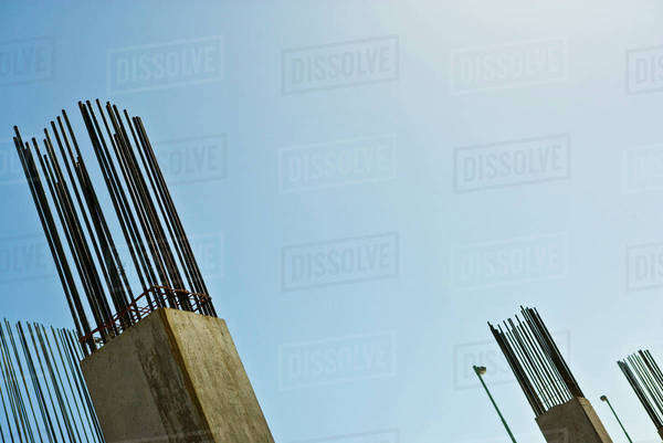 Exposed rebar protruding from unfinished concrete column against blue ...
