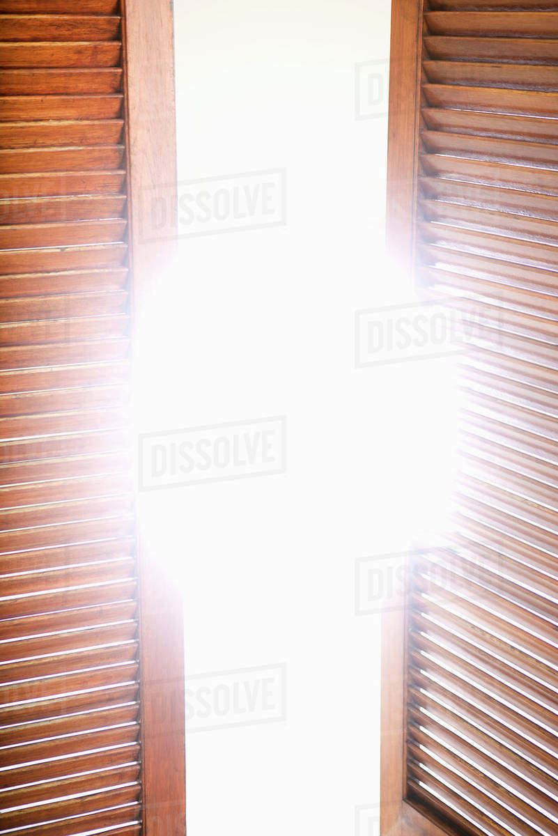 Wooden shutters partially opened to bright sunlight - Royalty-free ...