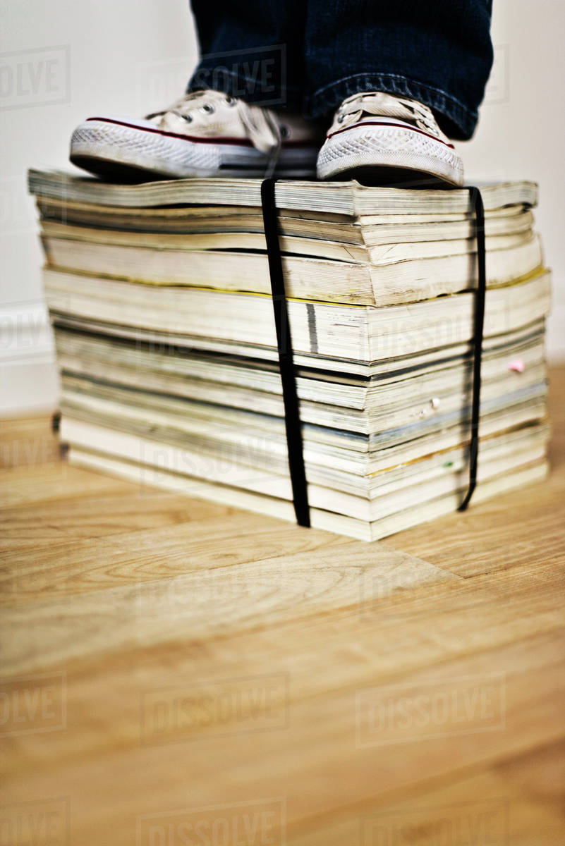 Person standing on top of bound stack of books and magazines - Royalty ...