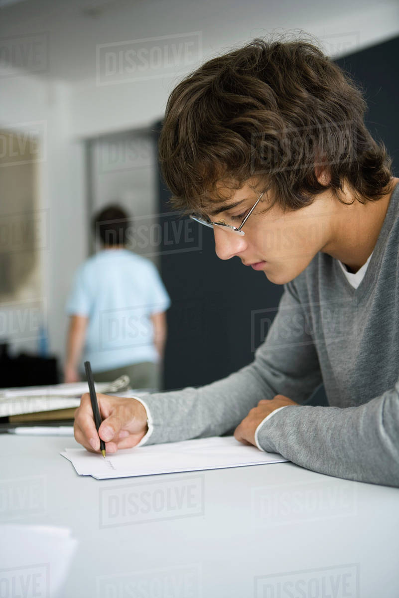 College student writing at desk in classroom - Royalty-free Stock Photo ...