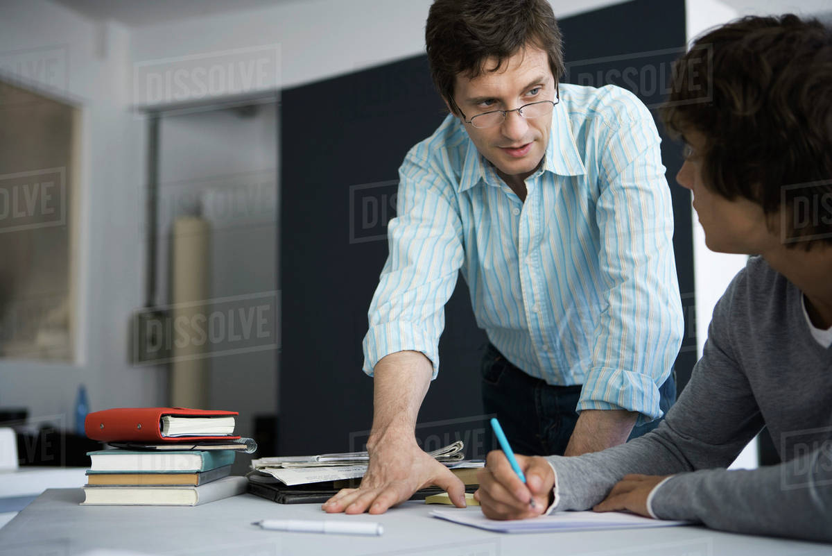 Teacher explaining assignment to student - Stock Photo - Dissolve