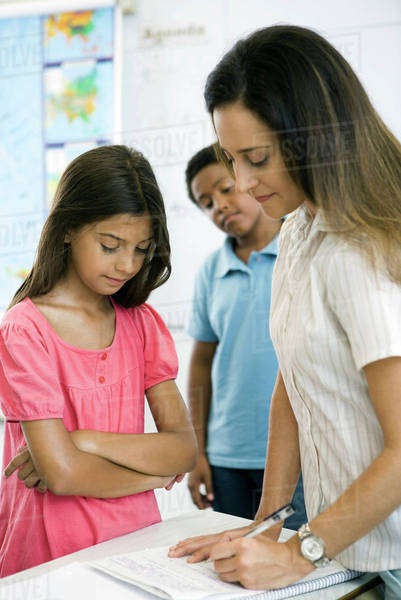 Elementary school student watching as teacher marks assignment - Stock ...