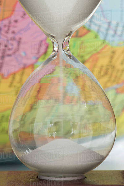 Hourglass, map in background - Stock Photo - Dissolve