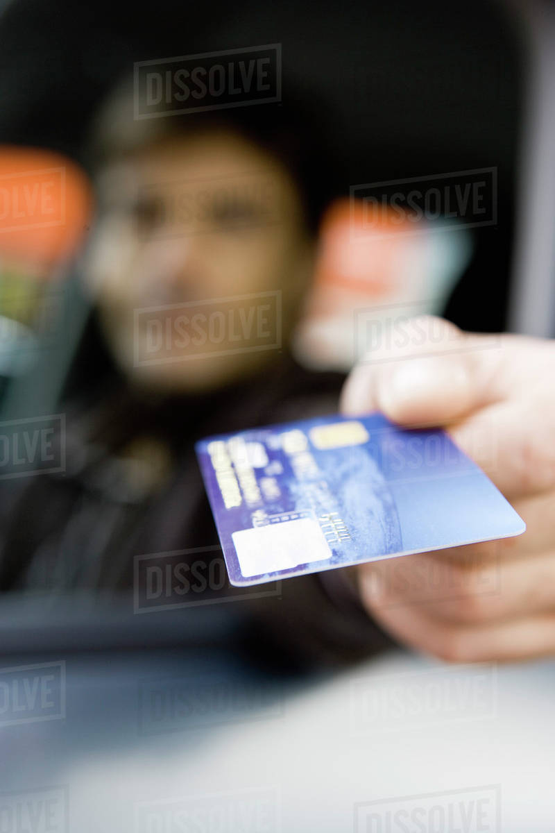 Customer in drive-thru holding out credit card - Stock Photo - Dissolve