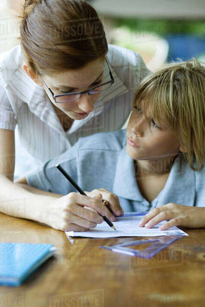 Teacher correcting student's classwork, student looking up at teacher ...