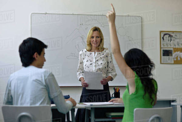High school teacher in classroom, one student raising hand - Royalty ...
