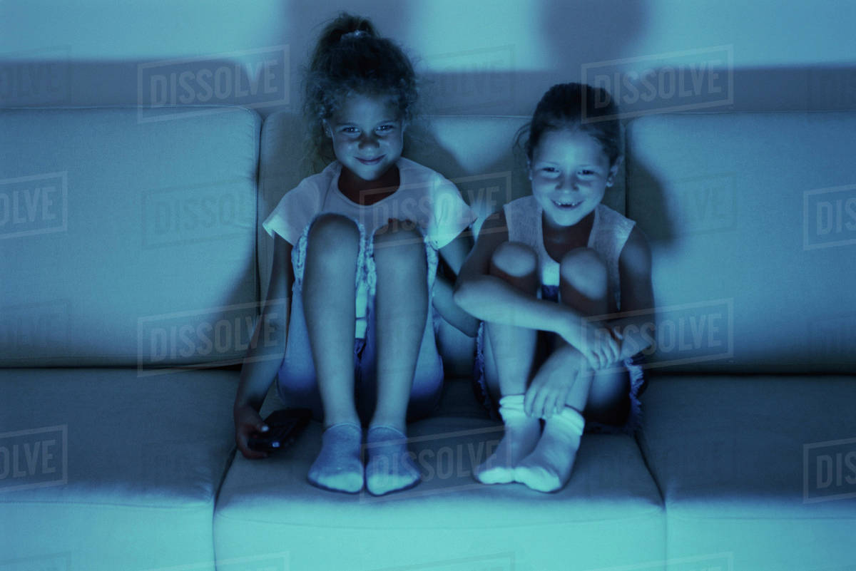 Two girls watching TV together at night, both smiling - Royalty-free ...