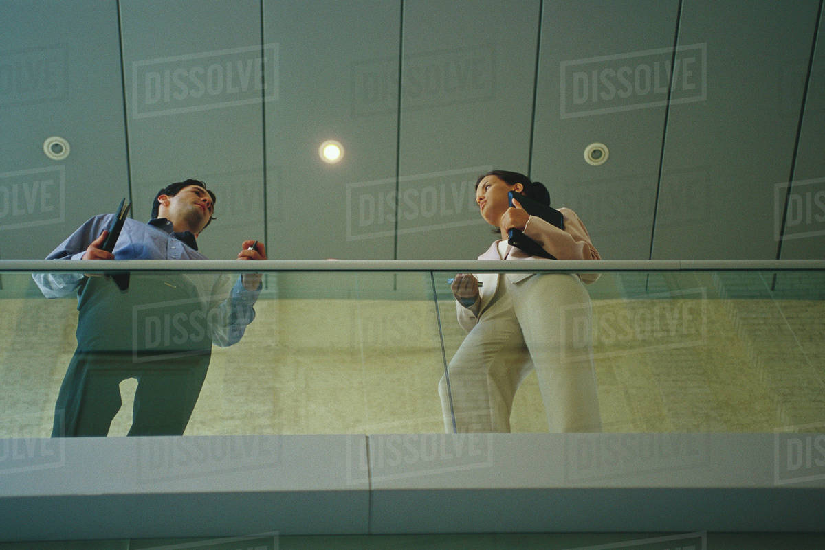 Colleagues talking on balcony, low angle view - Royalty-free Stock ...