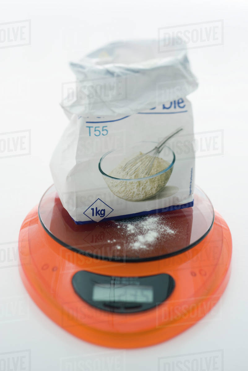 Weighing flour on kitchen scale - Stock Photo - Dissolve