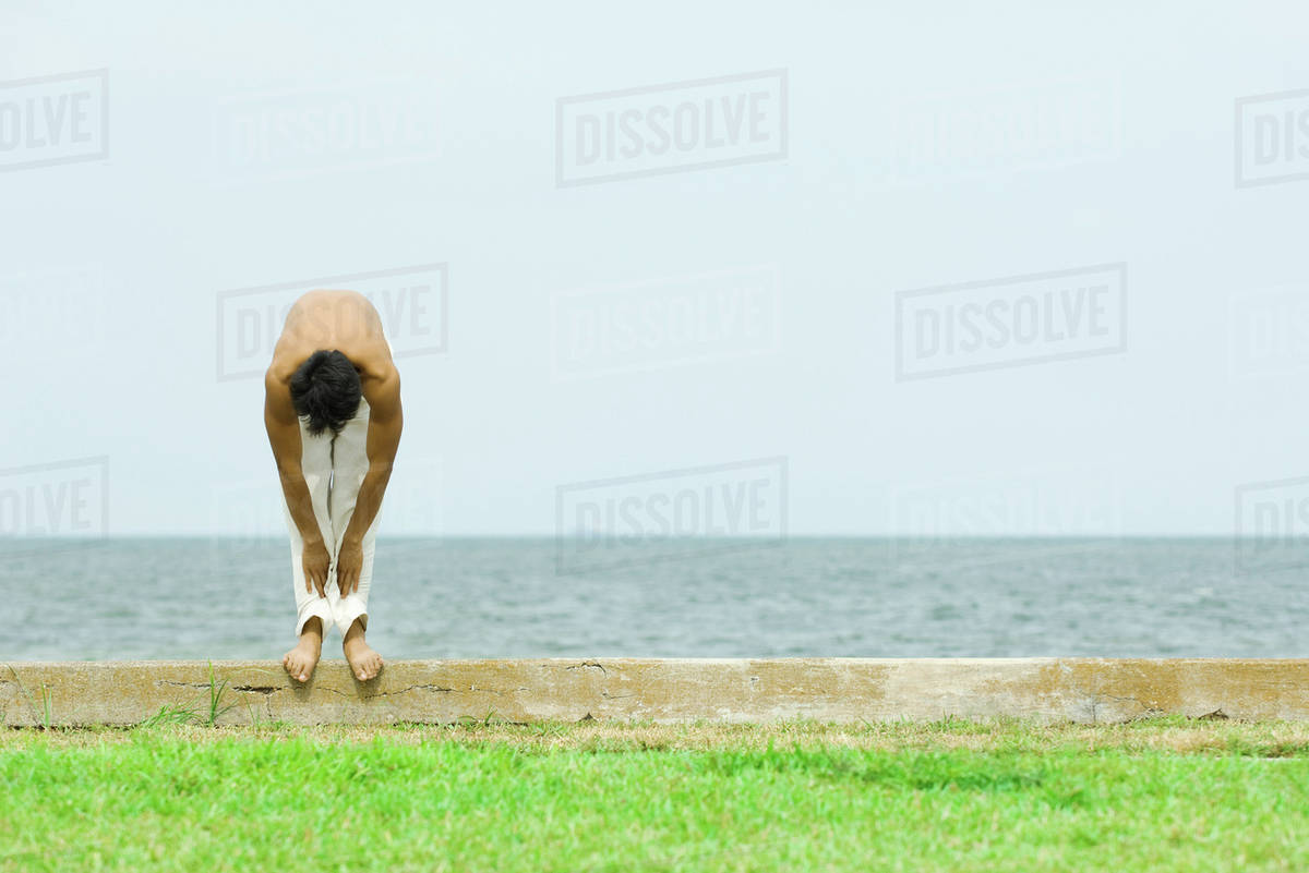 Man standing on low wall outdoors, bending over - Royalty-free Stock ...
