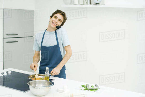 Young man cooking in kitchen, using cell phone - Royalty-free Stock ...