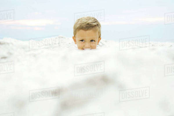 Boy's head emerging from sand - Stock Photo - Dissolve