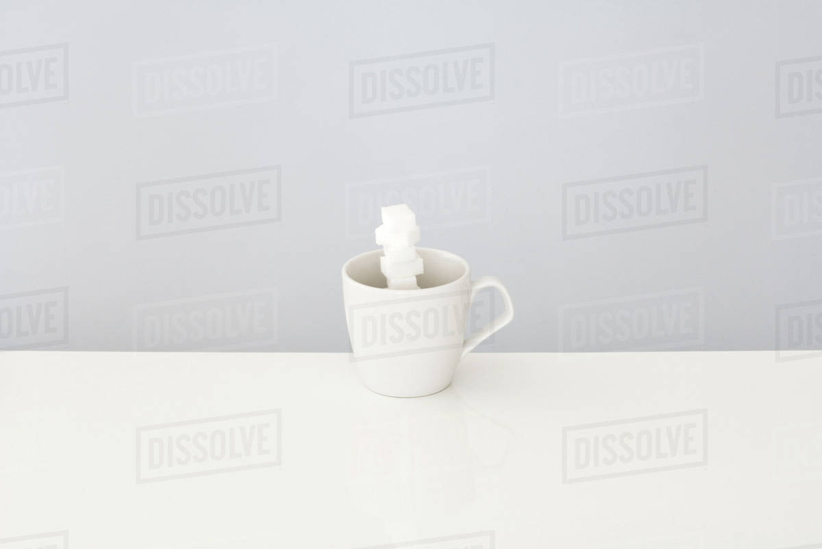 Sugar cubes stacked inside coffee cup - Royalty-free Stock Photo | Dissolve