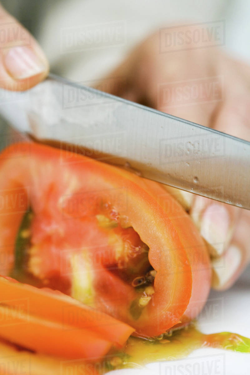 Woman slicing tomato with knife, cropped view of hand - Stock Photo ...