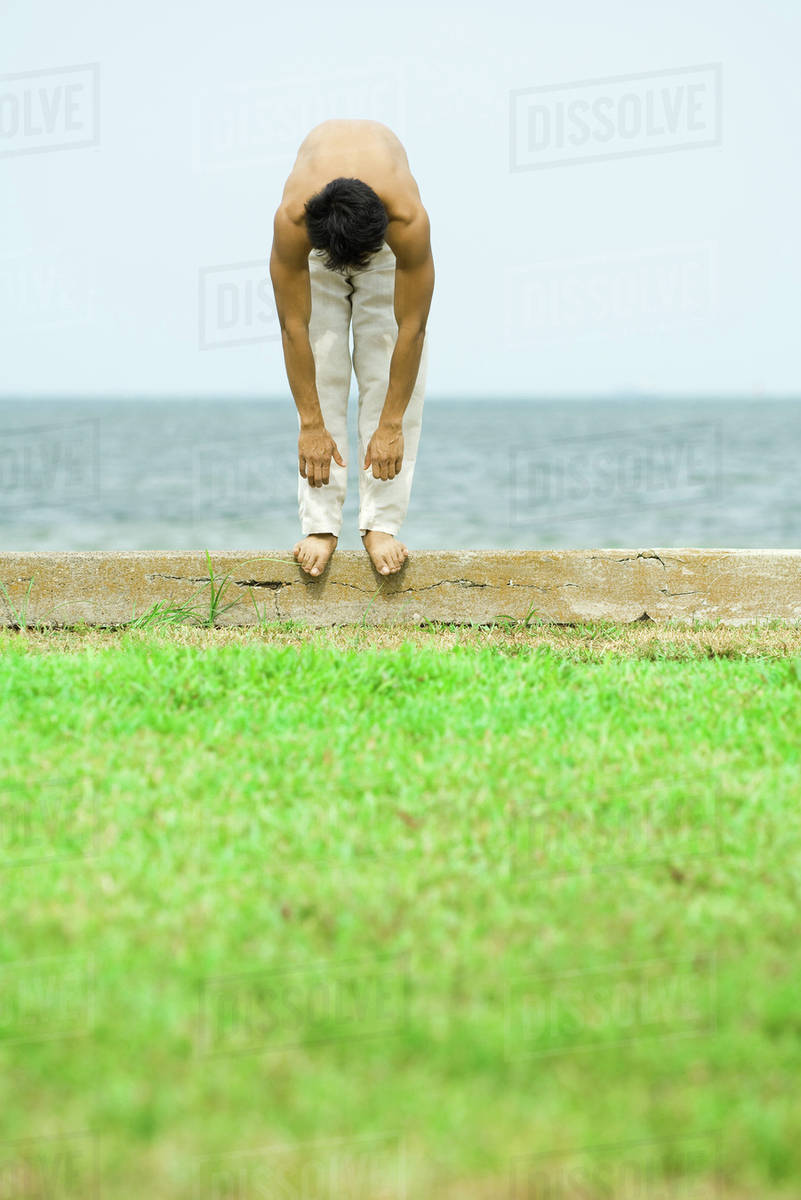 Man standing on low wall outdoors, bending over - Royalty-free Stock ...