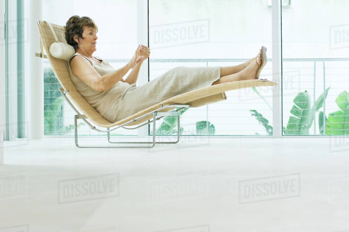 Woman reclining on lounge chair, side view - Royalty-free Stock Photo ...