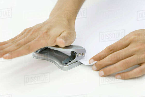 Hands using hole puncher - Stock Photo - Dissolve
