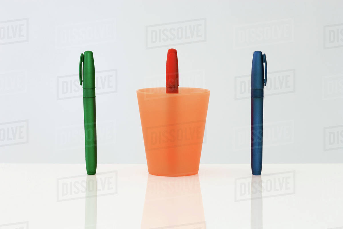 Pens standing upright in a row, the middle pen upside down inside of ...