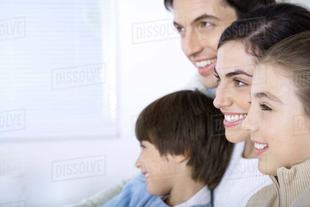 Family sitting together, looking away, side view - Stock Photo - Dissolve