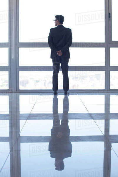 Man standing in front of window, looking at view - Royalty-free Stock ...