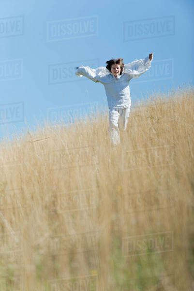 Boy running through tall grass - Stock Photo - Dissolve