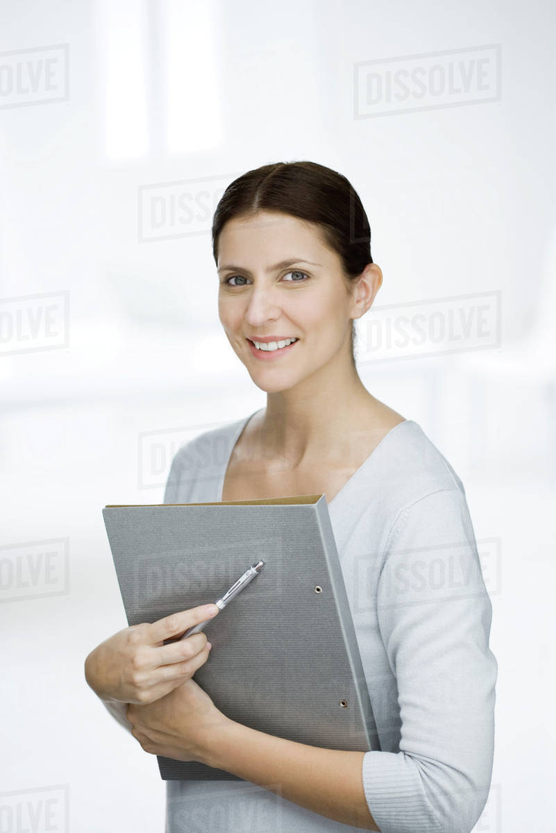 Woman holding folder, smiling at camera, portrait - Royalty-free Stock ...