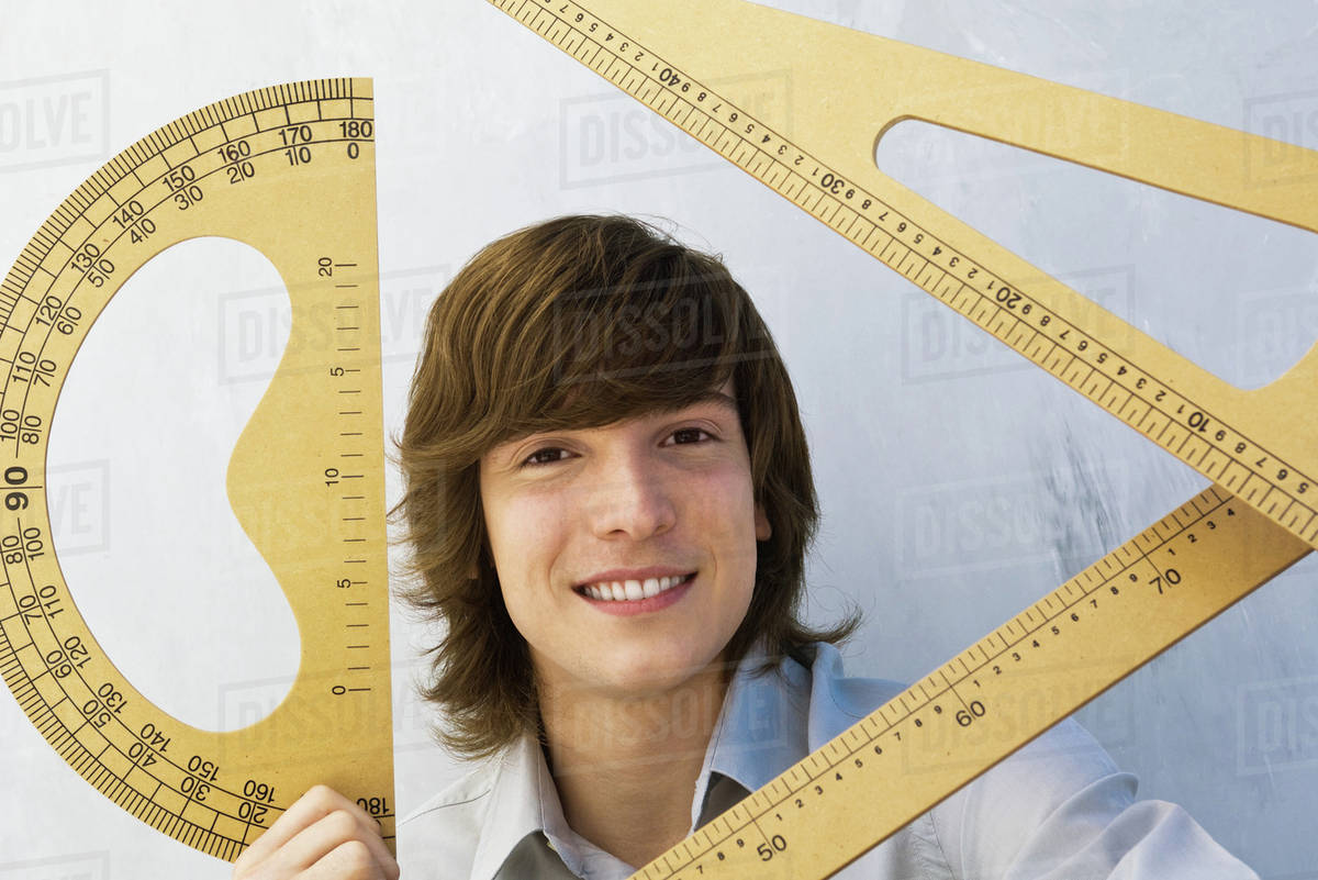 Young man holding various measuring instruments, smiling at camera ...