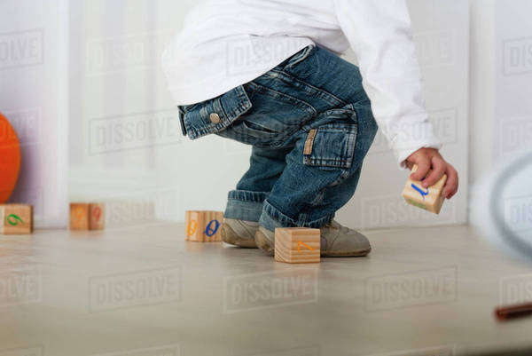 Baby picking up block from floor, low section - Stock Photo - Dissolve