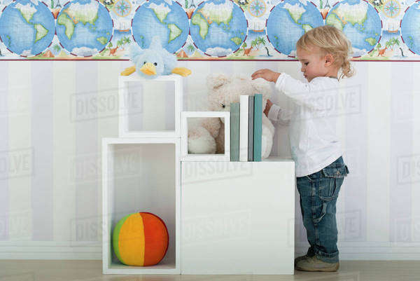 Baby boy standing by shelves with toys - Royalty-free Stock Photo ...