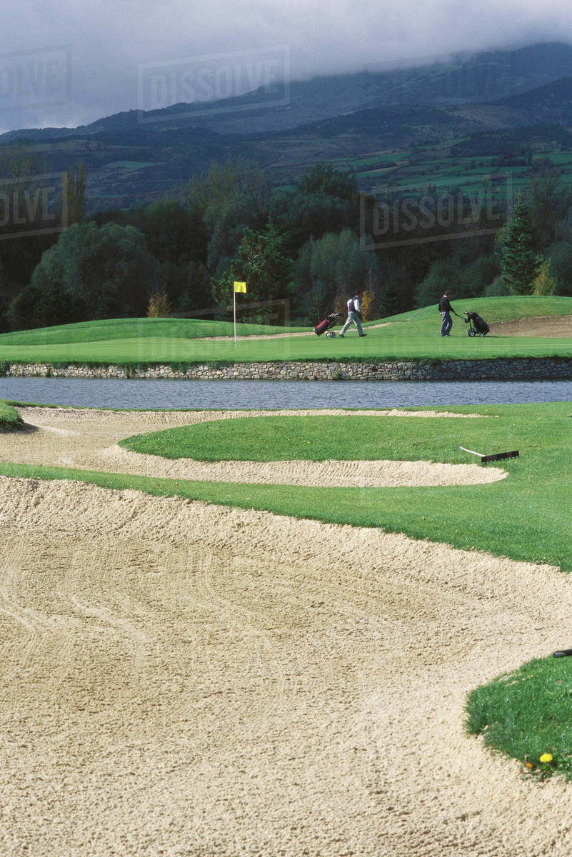 Golfers on golf course, sand trap in foreground - Stock Photo - Dissolve