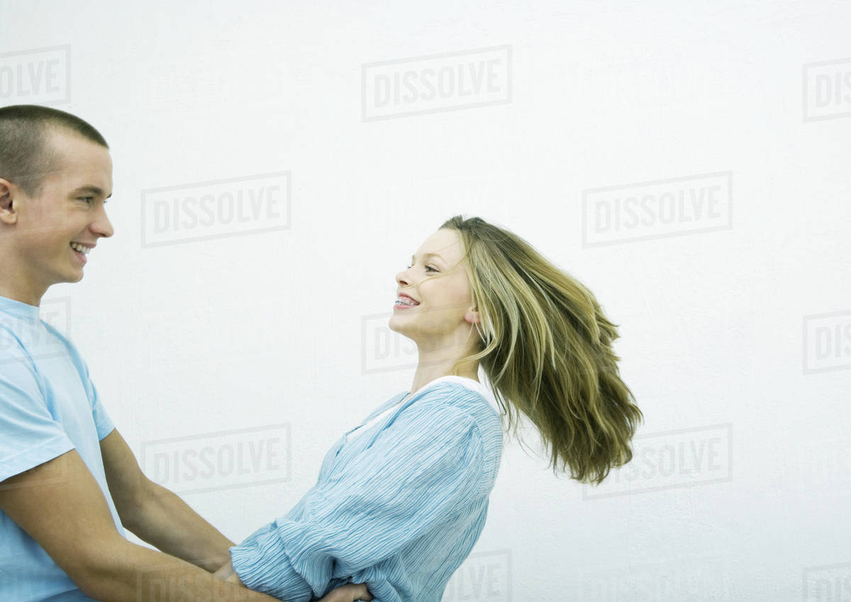 Young couple spinning around, white background - Stock Photo - Dissolve