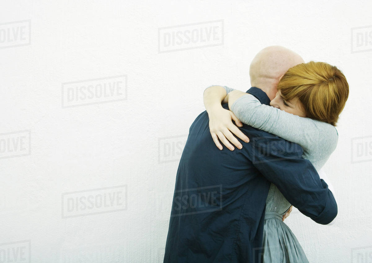 Young couple embracing, side view - Stock Photo - Dissolve