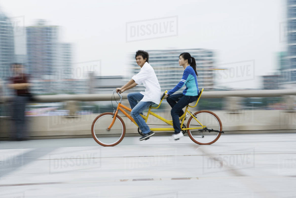Couple riding tandem bicycle - Stock Photo - Dissolve