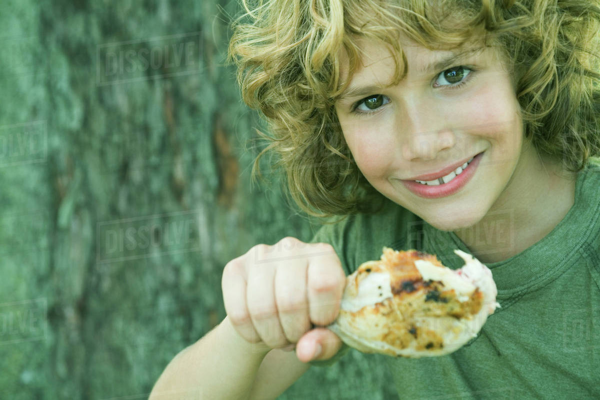 Boy holding grilled chicken leg, smiling at camera, portrait - Royalty ...
