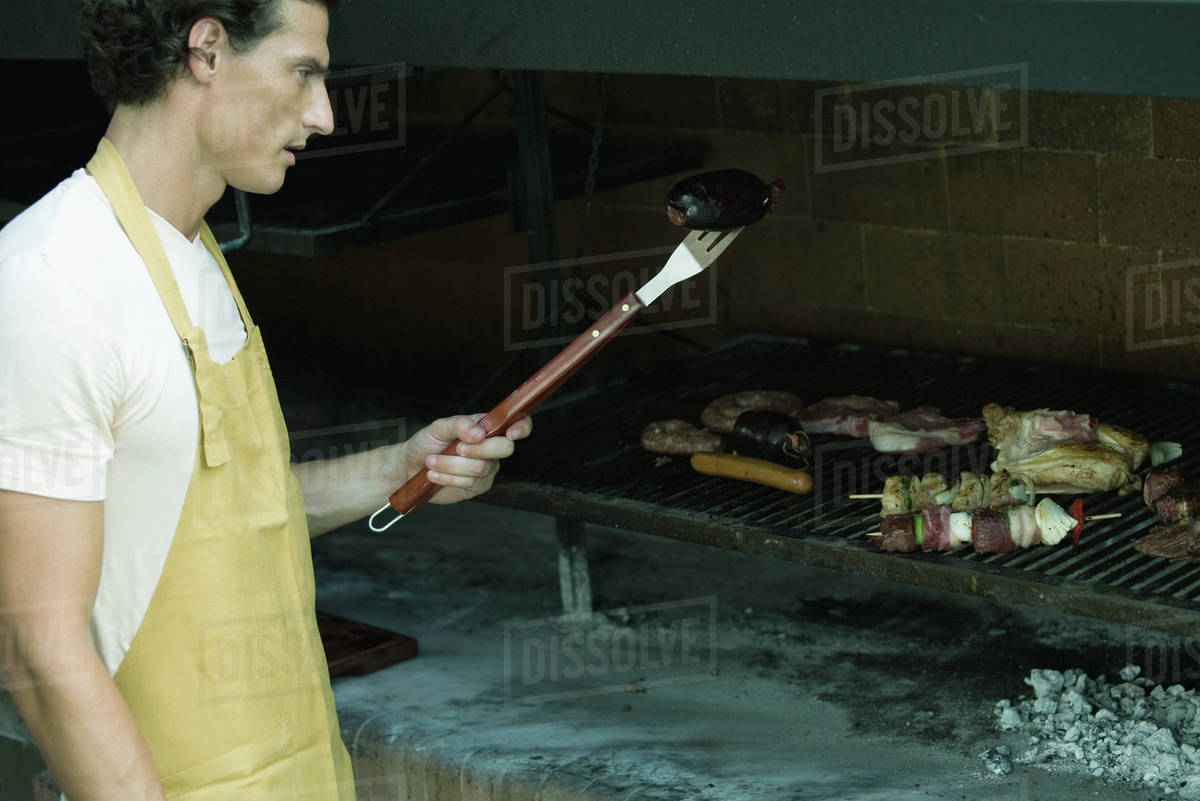 Man grilling meat on barbecue - Royalty-free Stock Photo | Dissolve