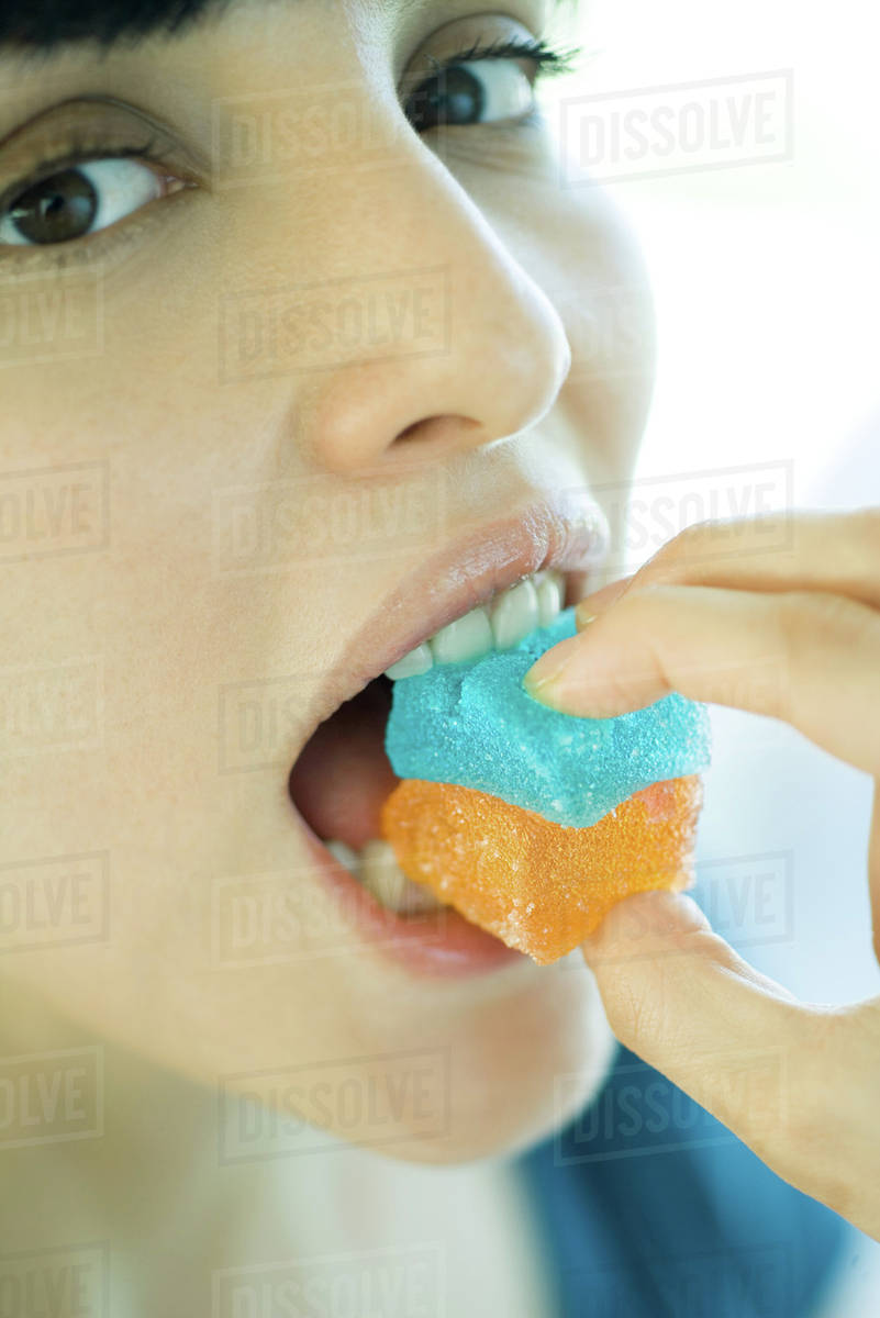 Woman biting into candy, close-up - Stock Photo - Dissolve